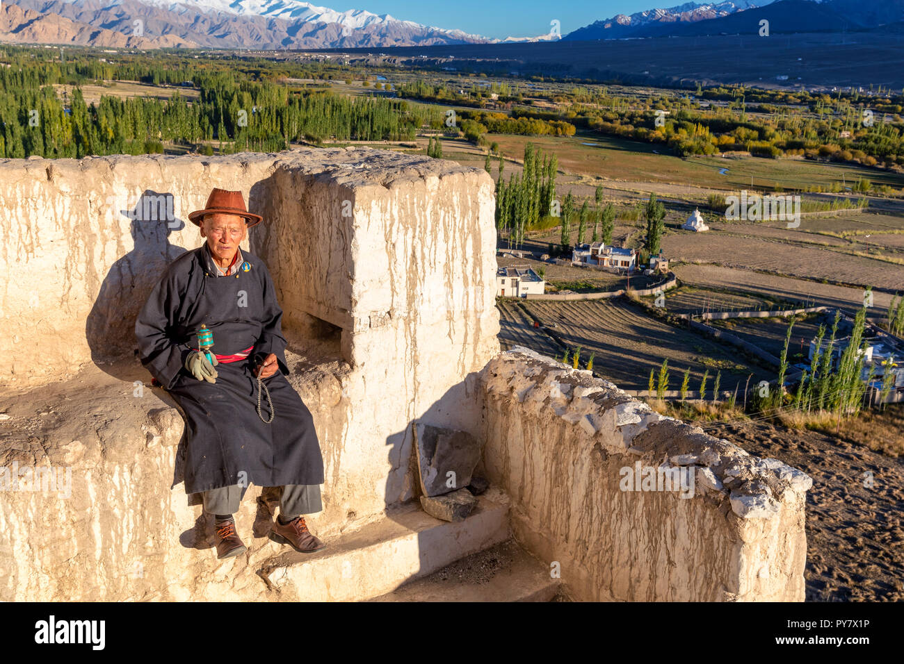 Elderly man resting and with a prayer wheel, Spituk Gompa, Leh district ...