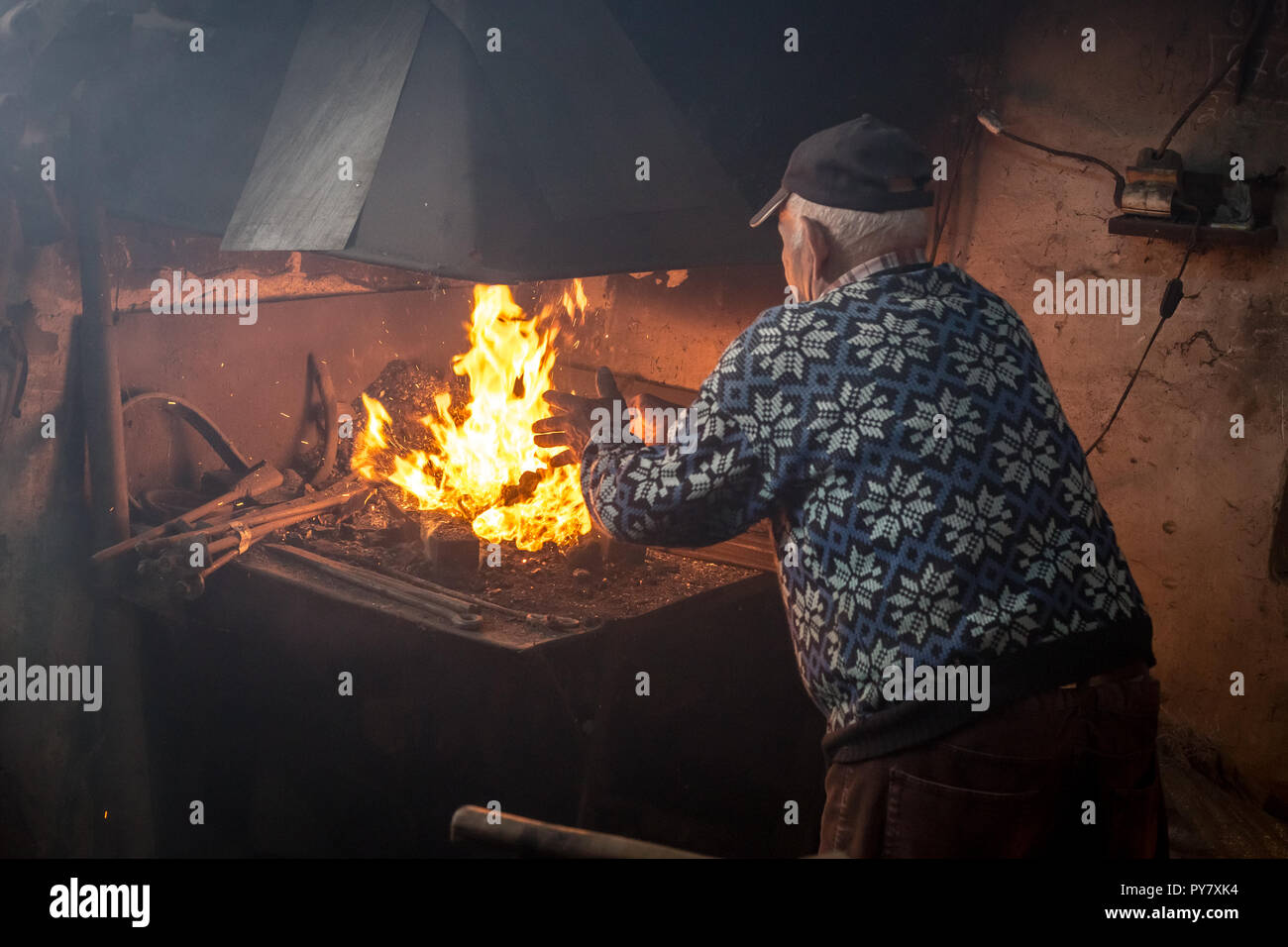 Old blacksmith burning coal. Blacksmith setting fire for forging metal ...