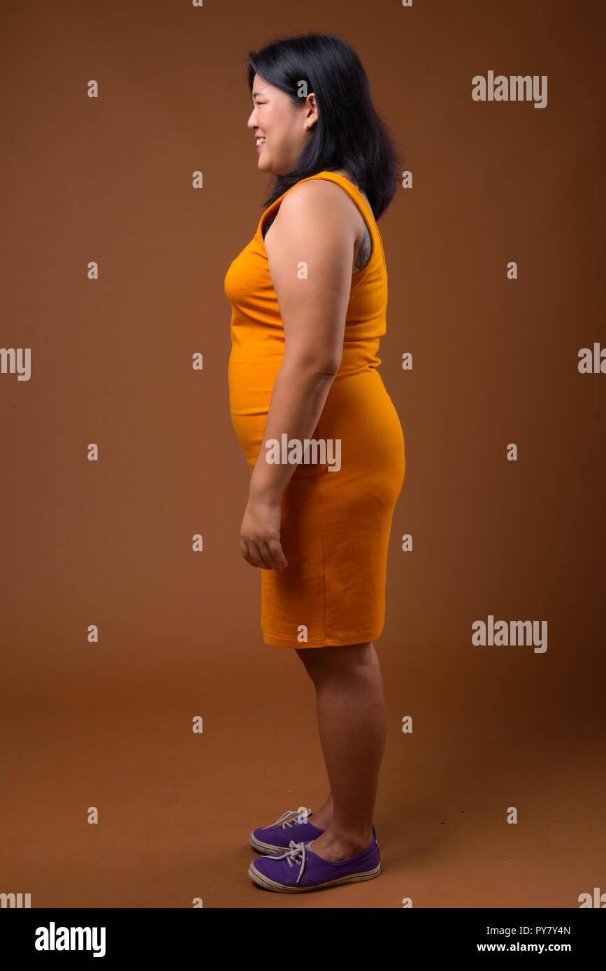 Full length profile view of beautiful overweight Asian woman smiling ...
