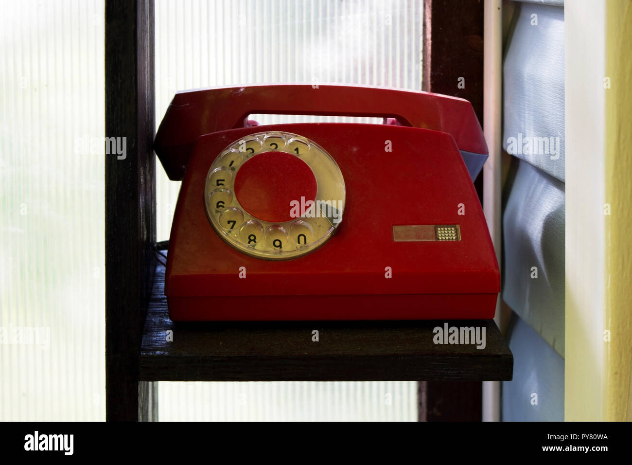 Vintage dusty red rotary telephone on the shelf as part of the ...