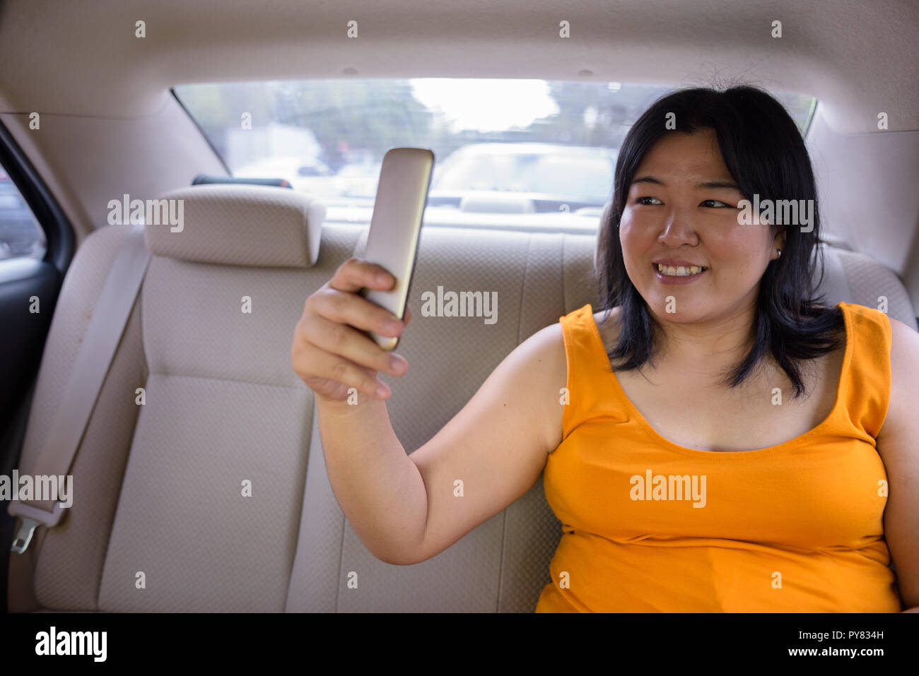 Happy Overweight Asian Woman Using Mobile To Take Selfie In Car Stock