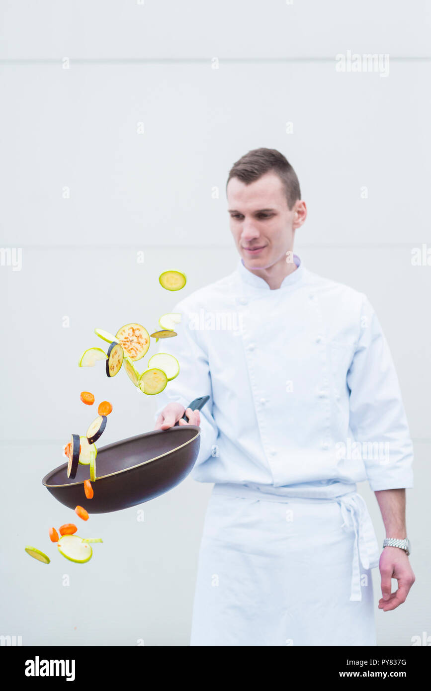 Young chef flipping vegetables in frying pan Stock Photo - Alamy