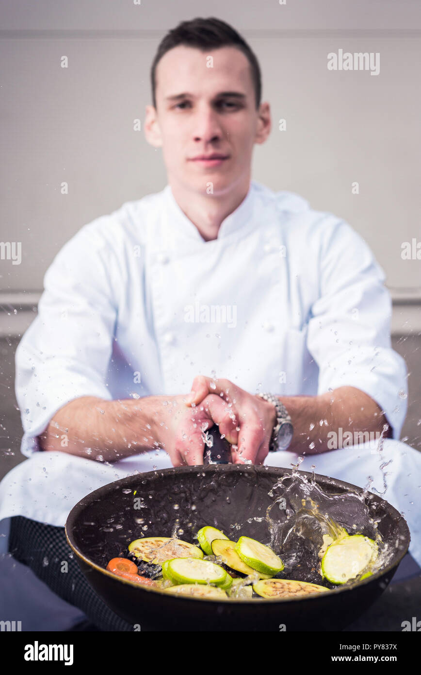 Young chef boiling in pan splashing vegetables Stock Photo - Alamy