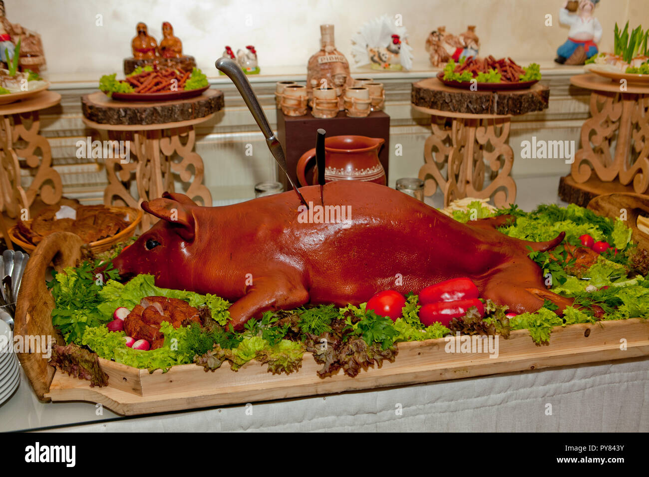 A young whole, baked pig, lying on a festive table decorated with herbs ...