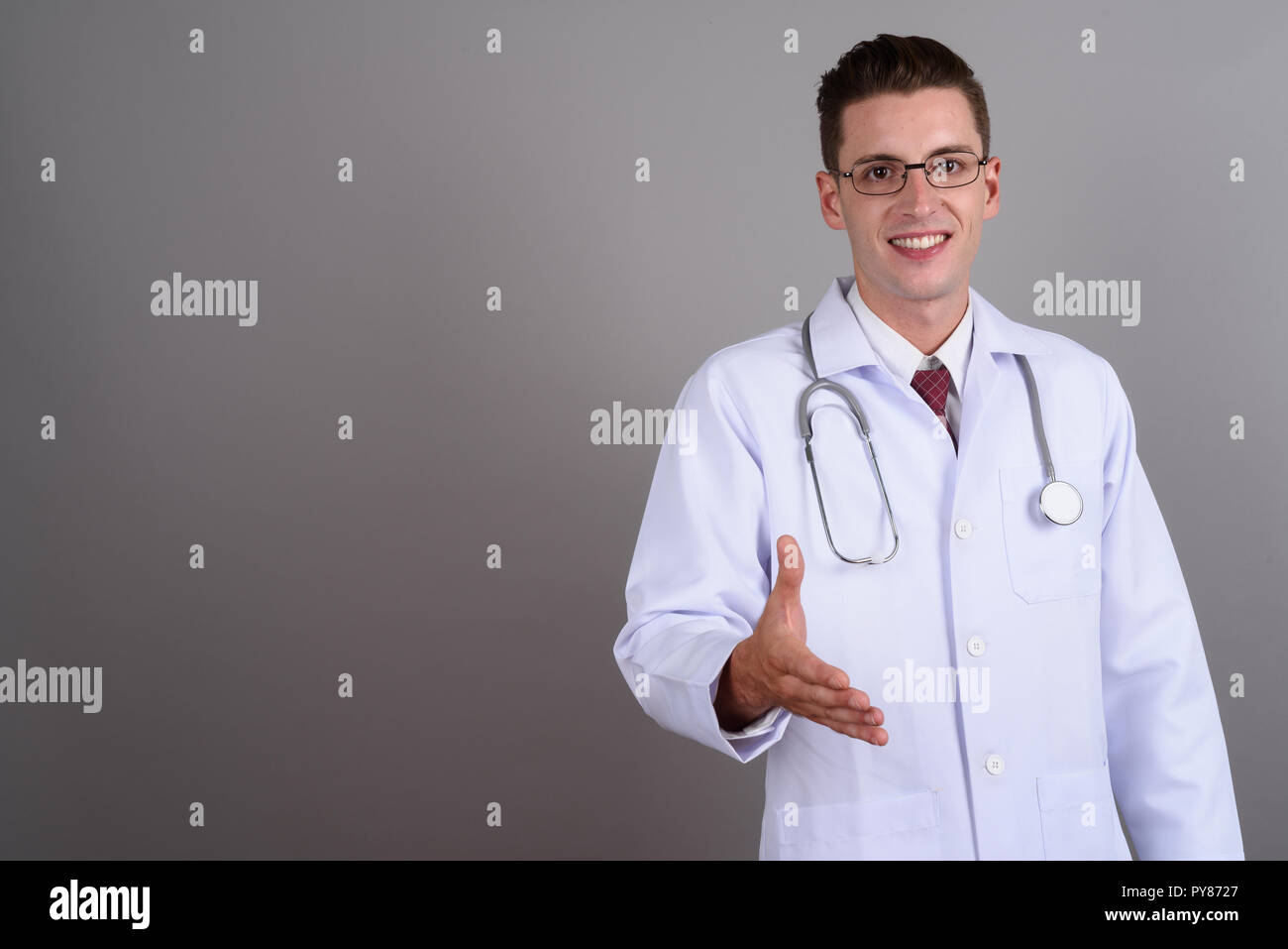 Young handsome man doctor smiling and giving handshake Stock Photo - Alamy