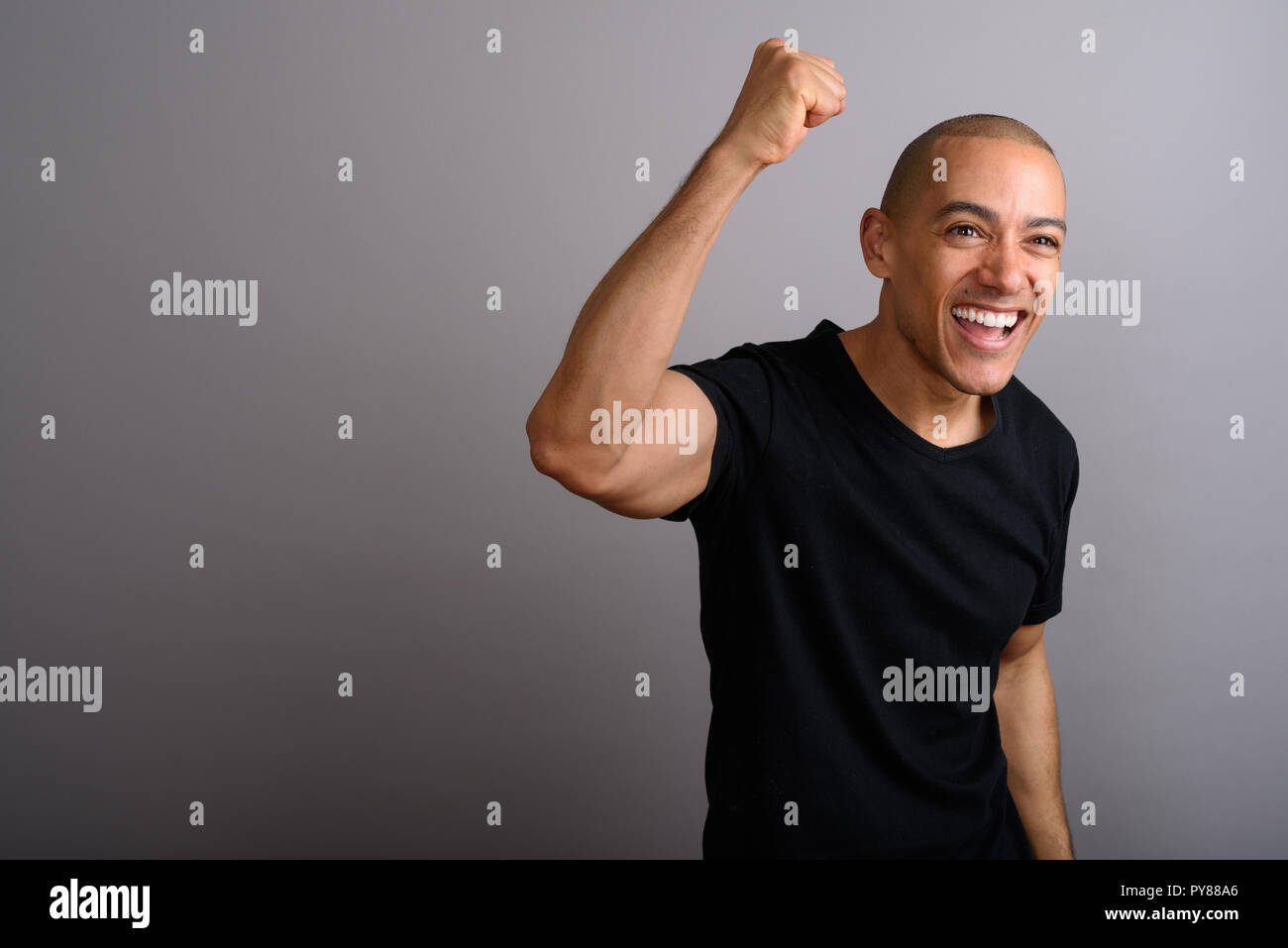 Handsome happy bald man smiling with arm raised Stock Photo - Alamy