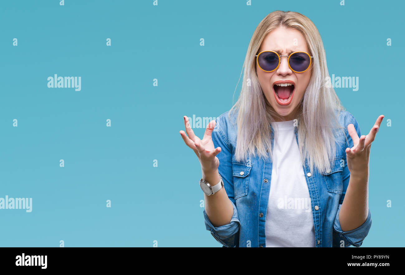 Young blonde woman wearing sunglasses over isolated background crazy ...