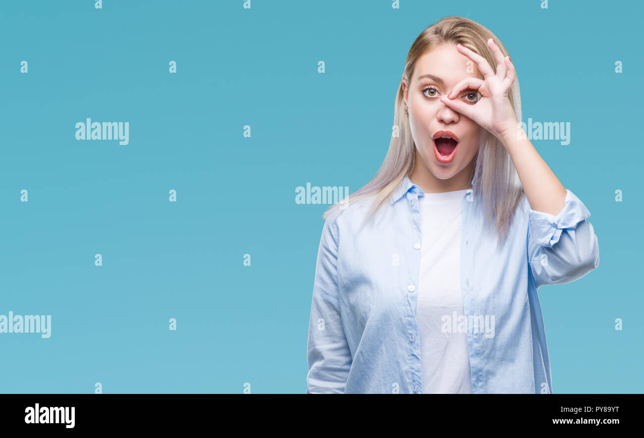 Young blonde woman over isolated background doing ok gesture shocked ...