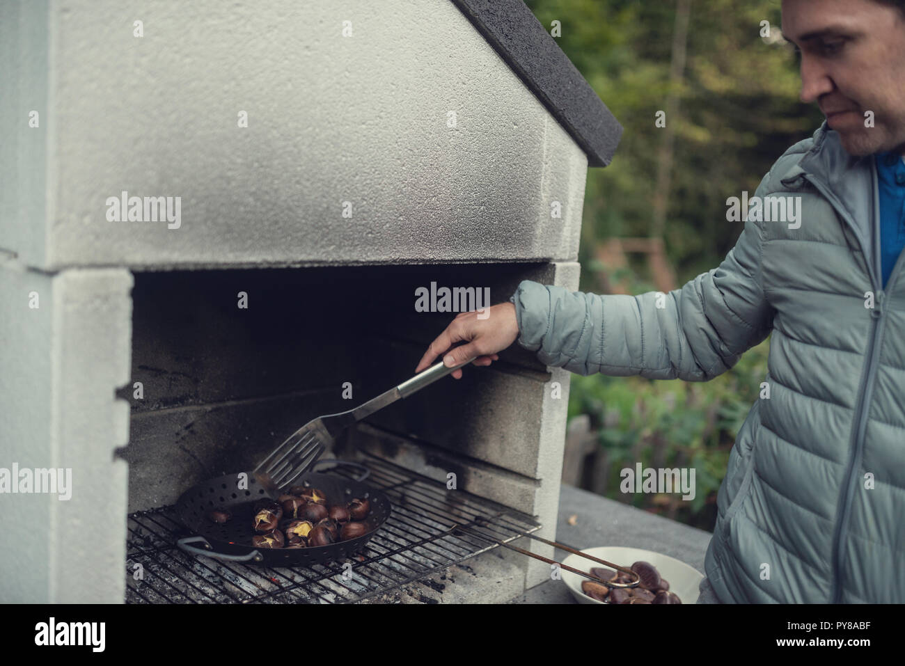 Retro image of a young man roasting delicious chestnuts outside in ...