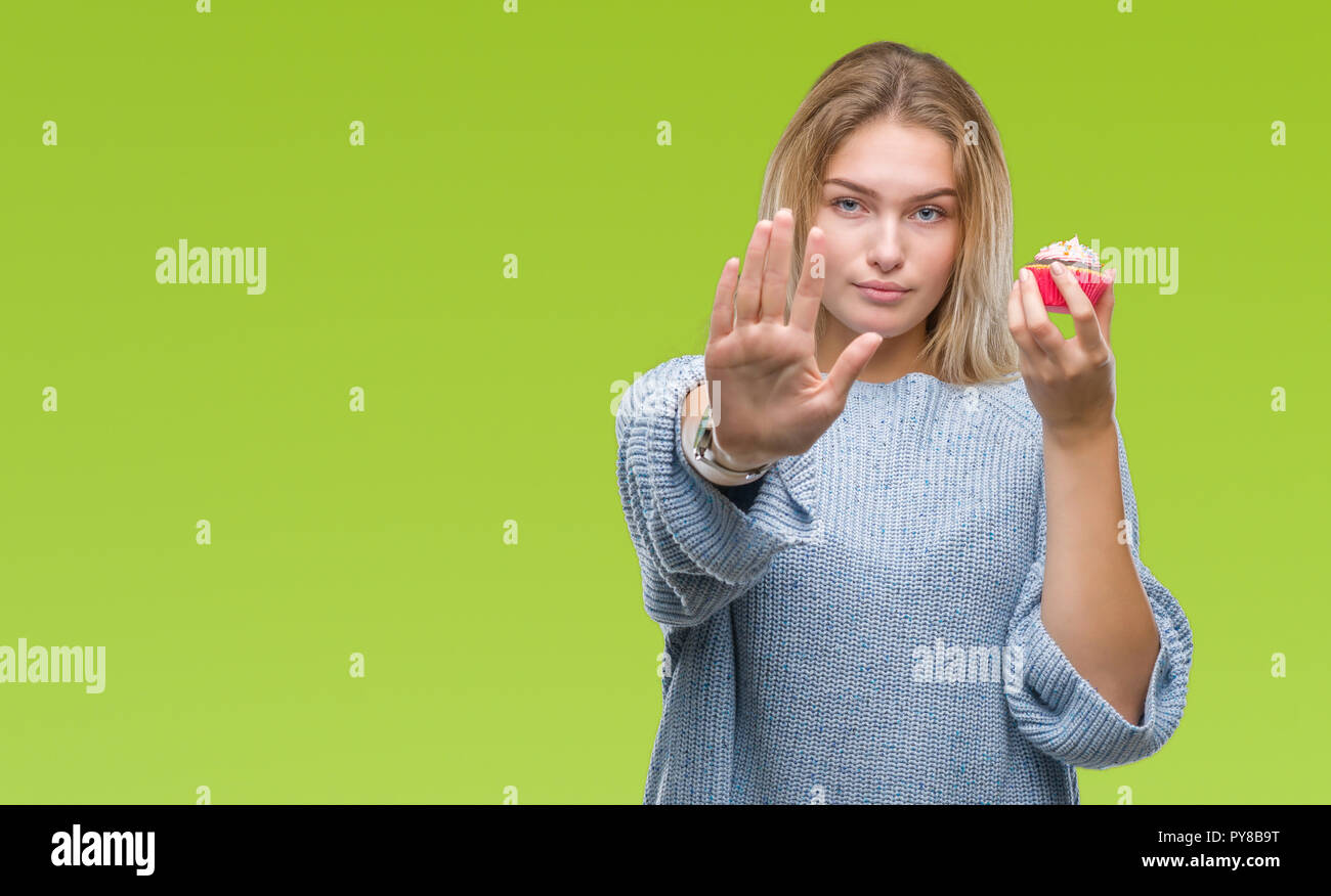 Young caucasian woman eating sweet cupcake over isolated background ...