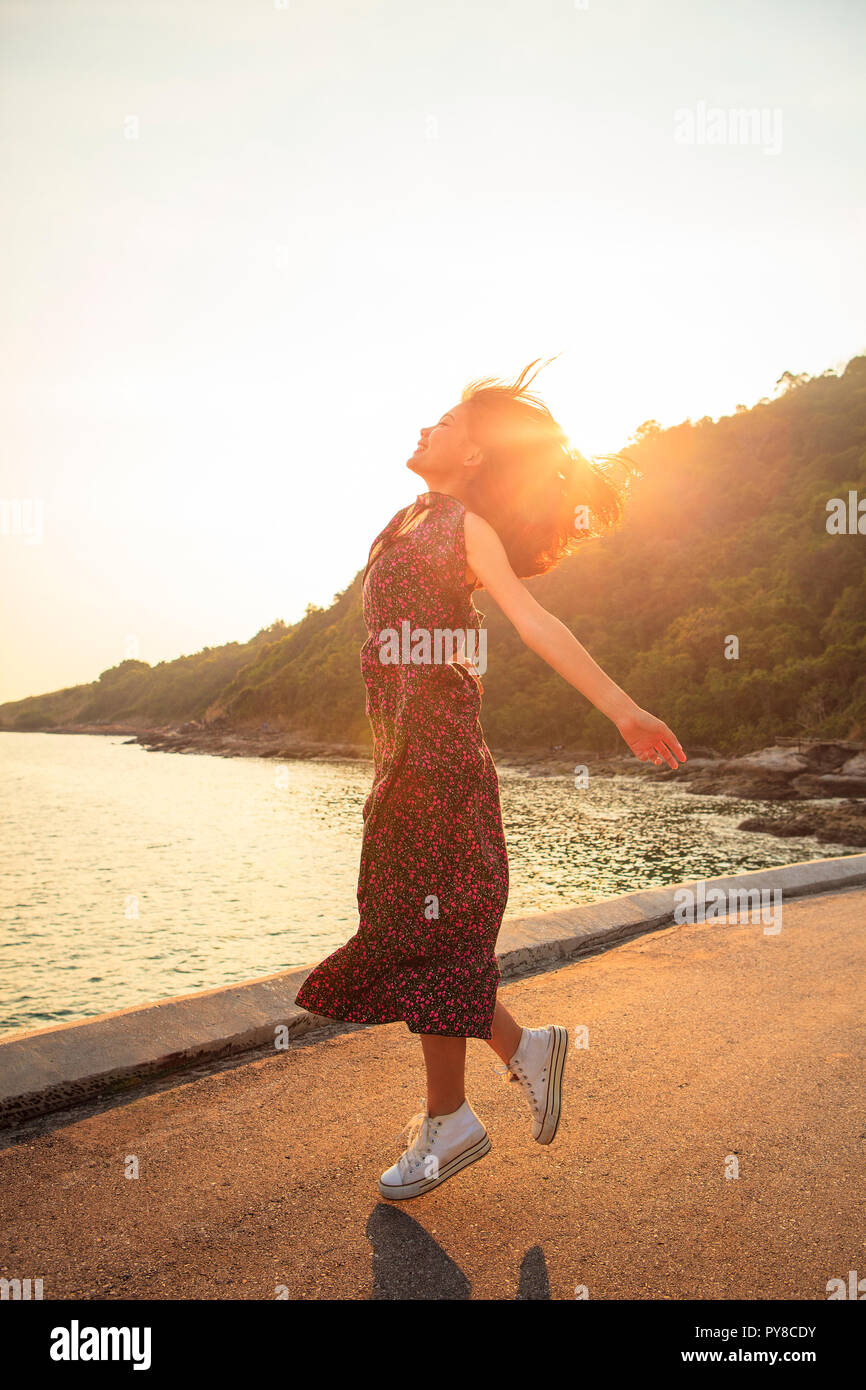 asian younger woman jumping and floating mid air against beautiful sun ...