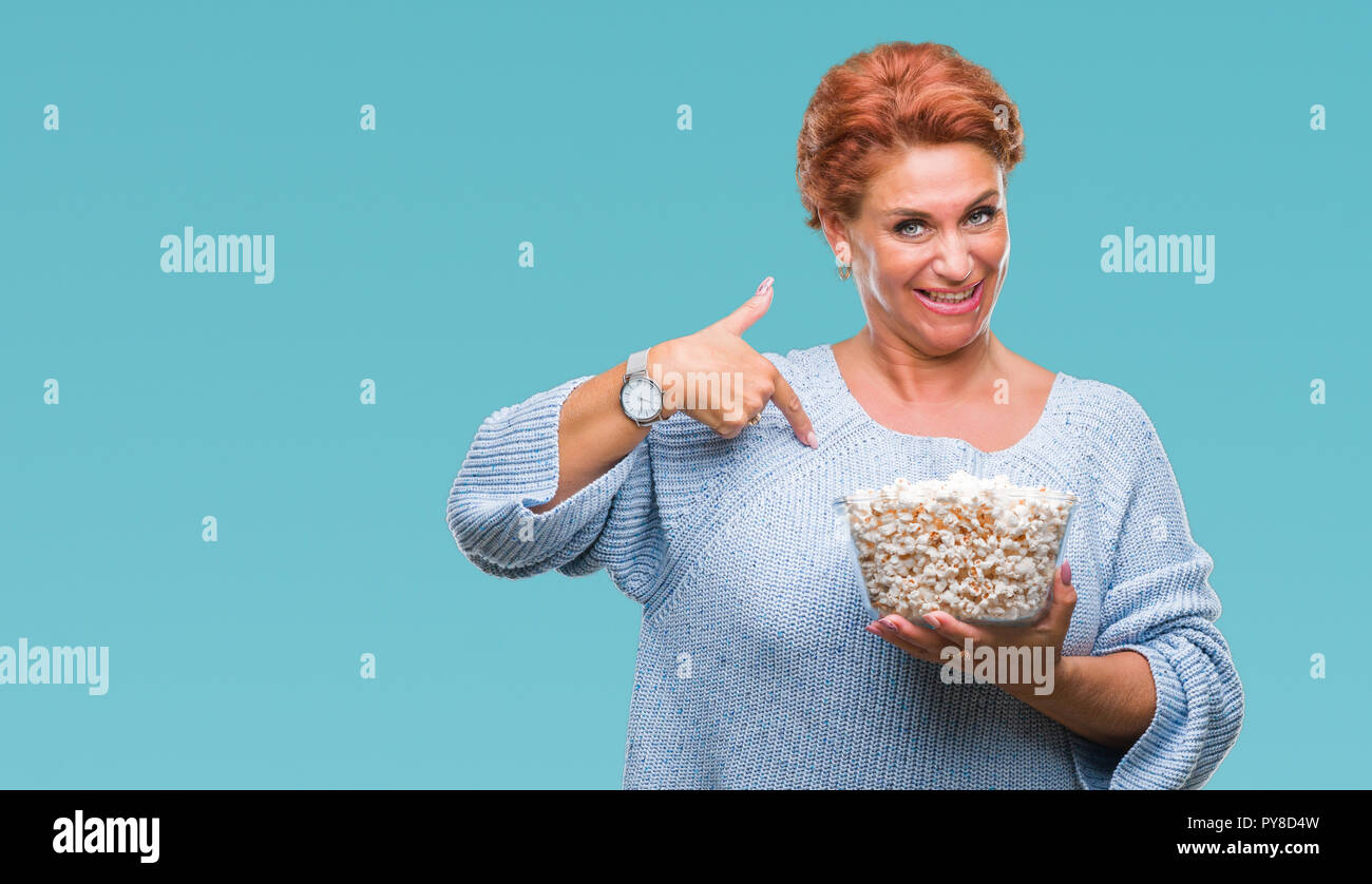 Atrractive Senior Caucasian Redhead Woman Eating Popcorn Over Isolated