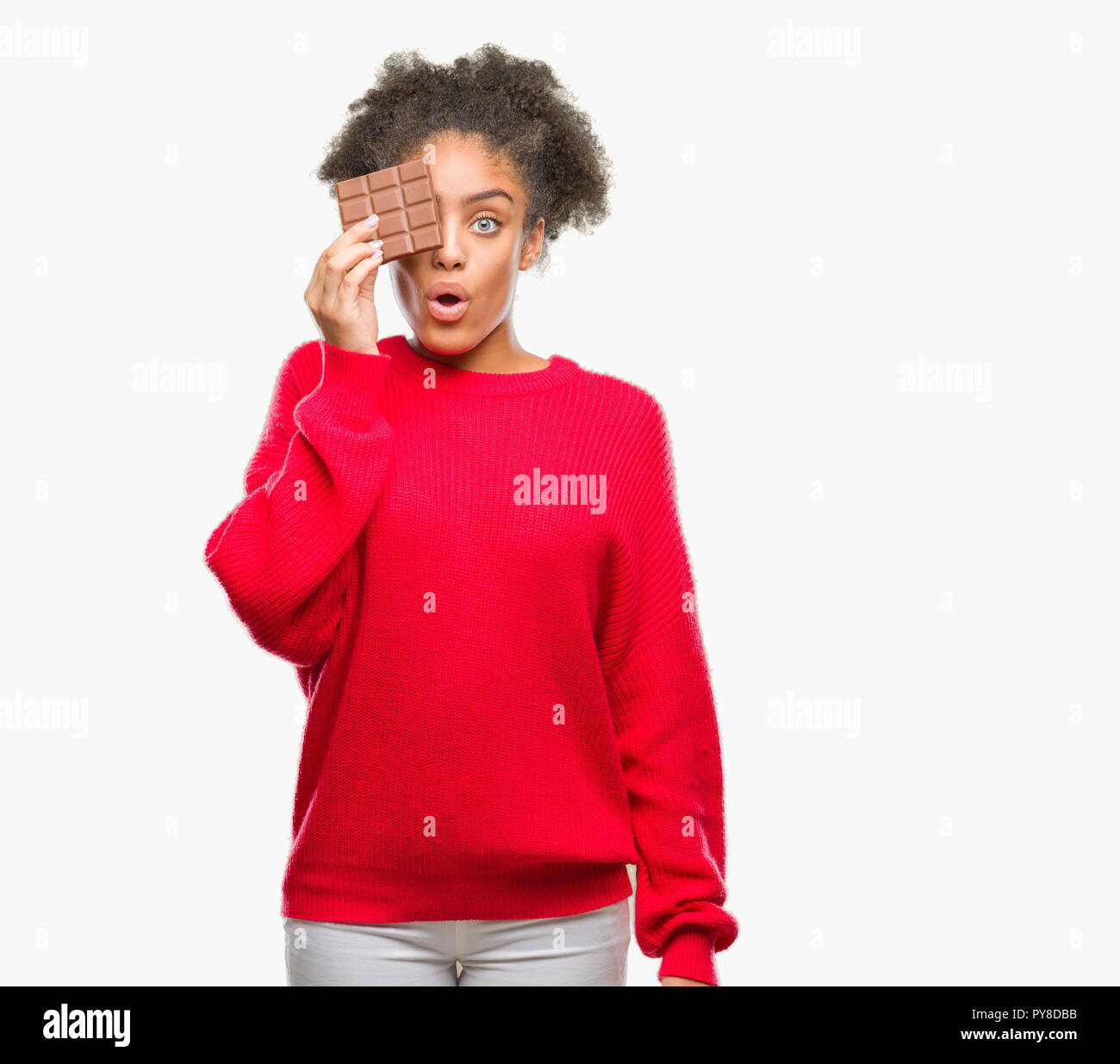 Young afro american woman eating chocolate bar over isolated background ...