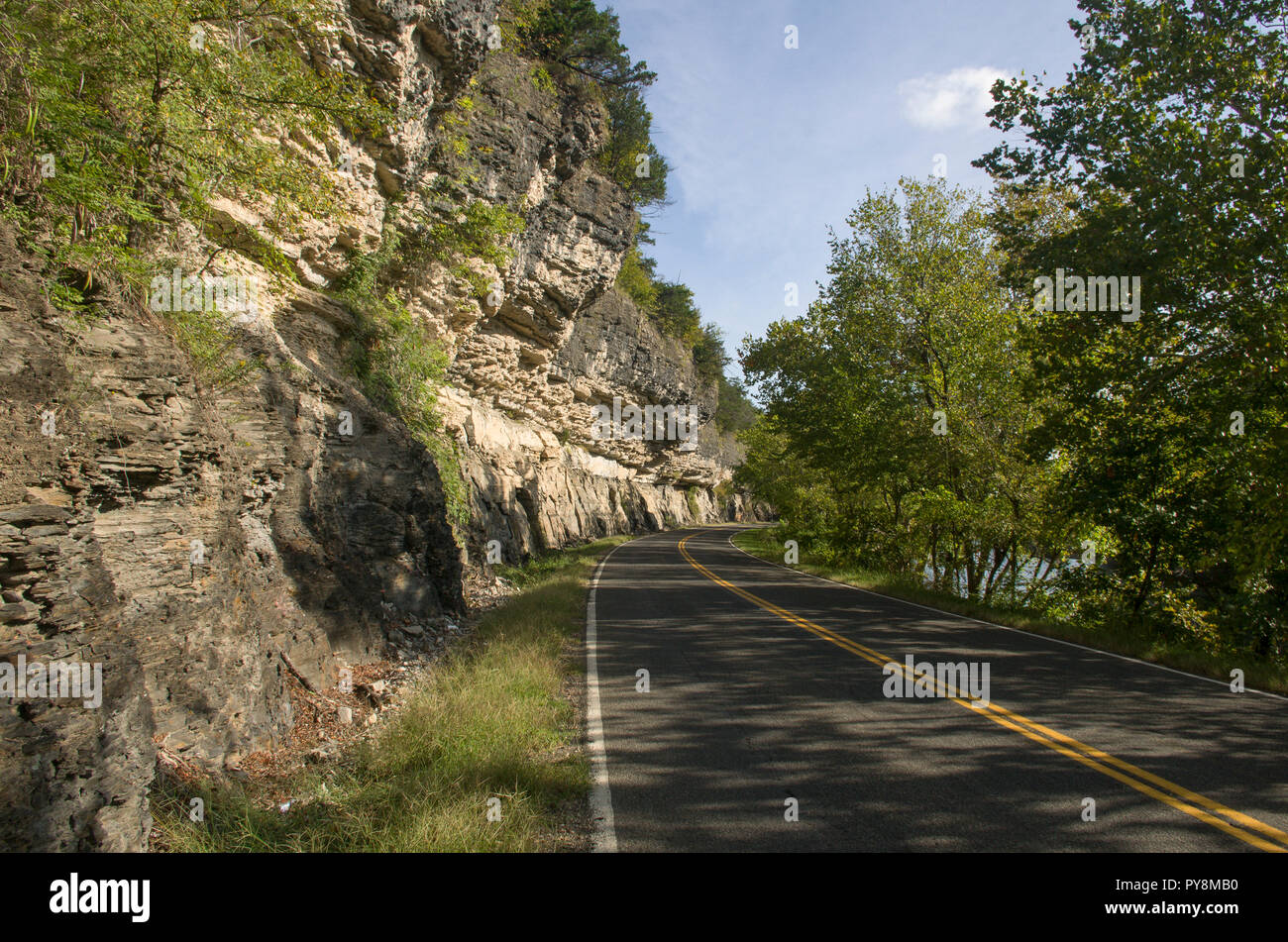 Curved two lane paved road beside beside large rock cliff Stock Photo ...