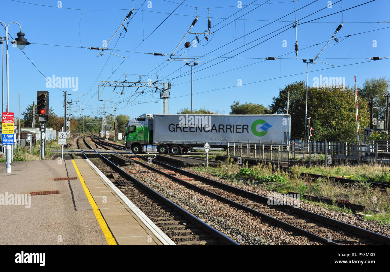 Vehicles traverse the level crossing at Ely railway station ...