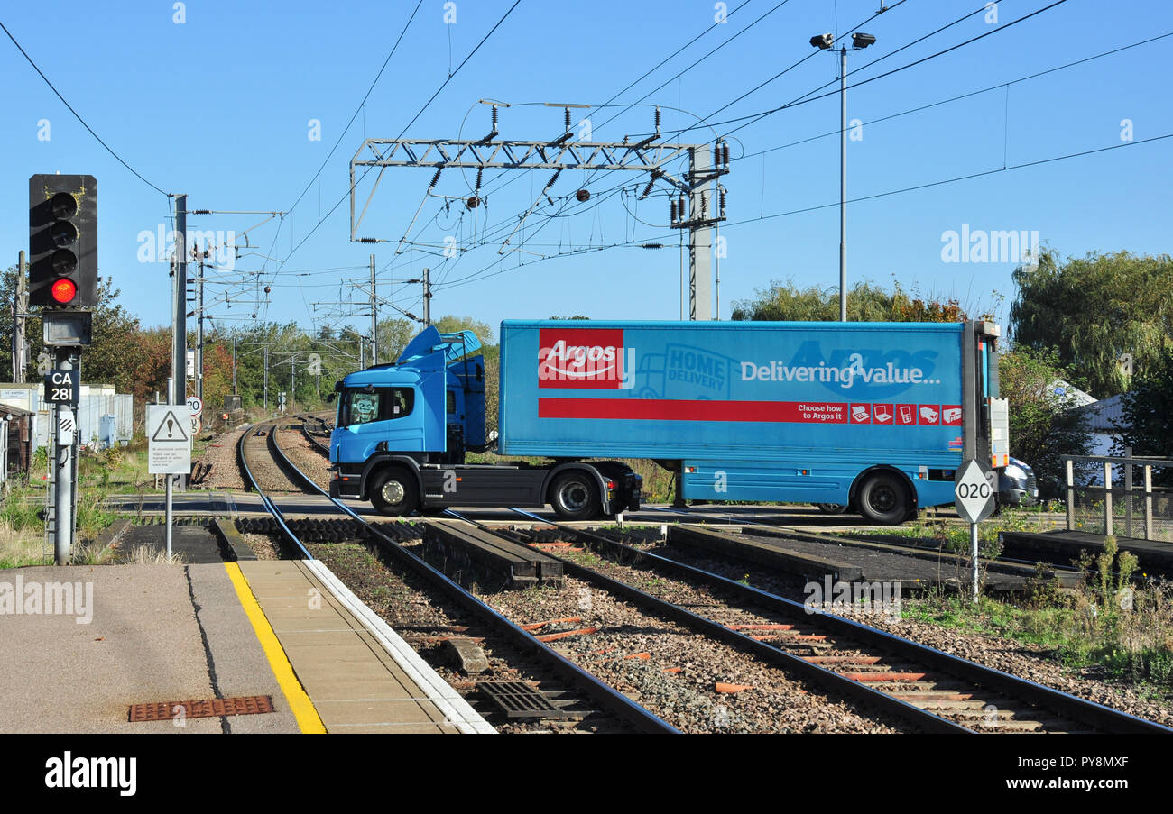 Vehicles traverse the level crossing at Ely railway station ...