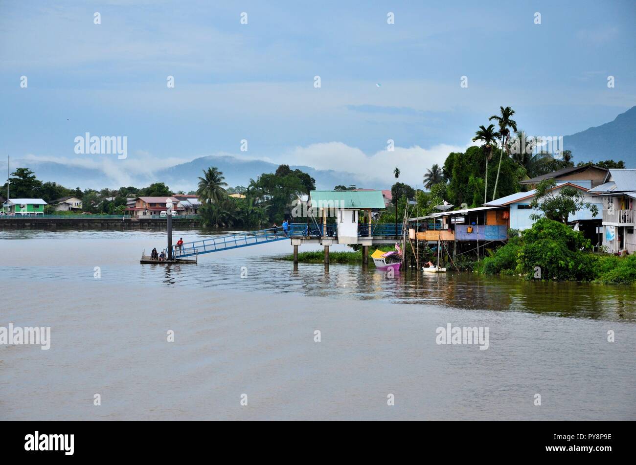 Malaysians from Sarawak riverside village on jetty with mountains ...