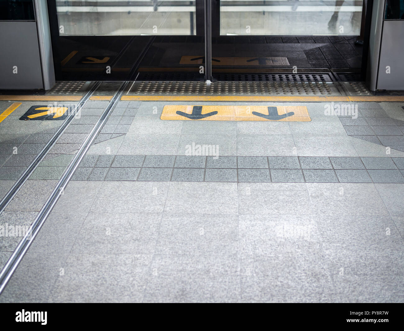 Waiting area on skytrain station. Yellow arrow sign pointing and safety ...