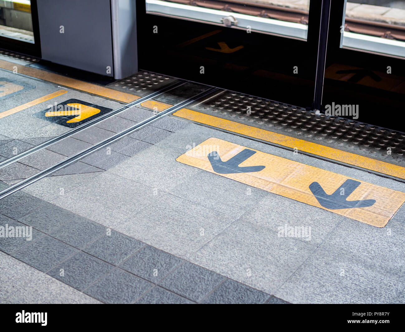Waiting area on skytrain station. Yellow arrow sign pointing and safety ...