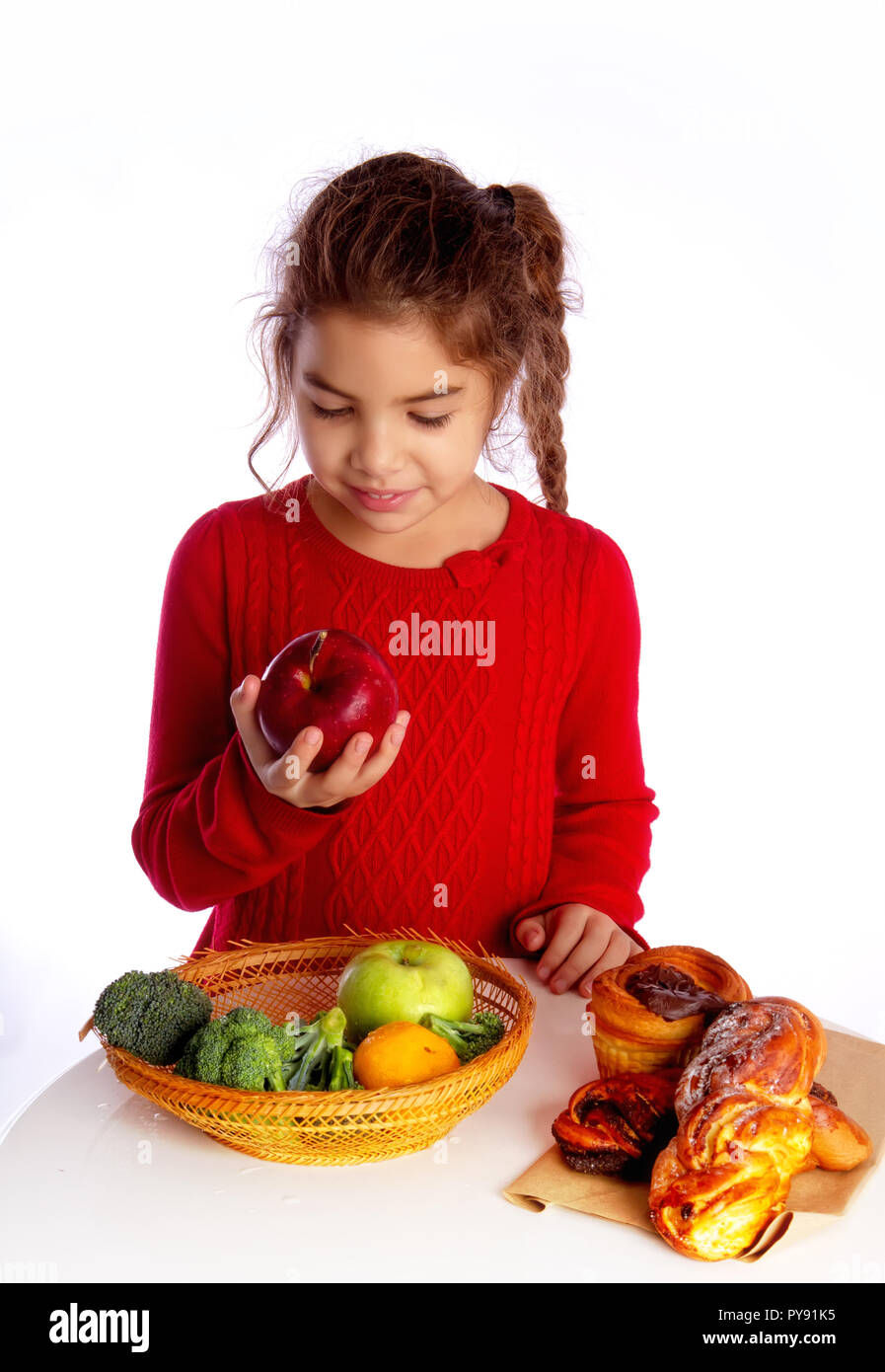 Little girl chooses what to eat, healthy food or buns Stock Photo - Alamy