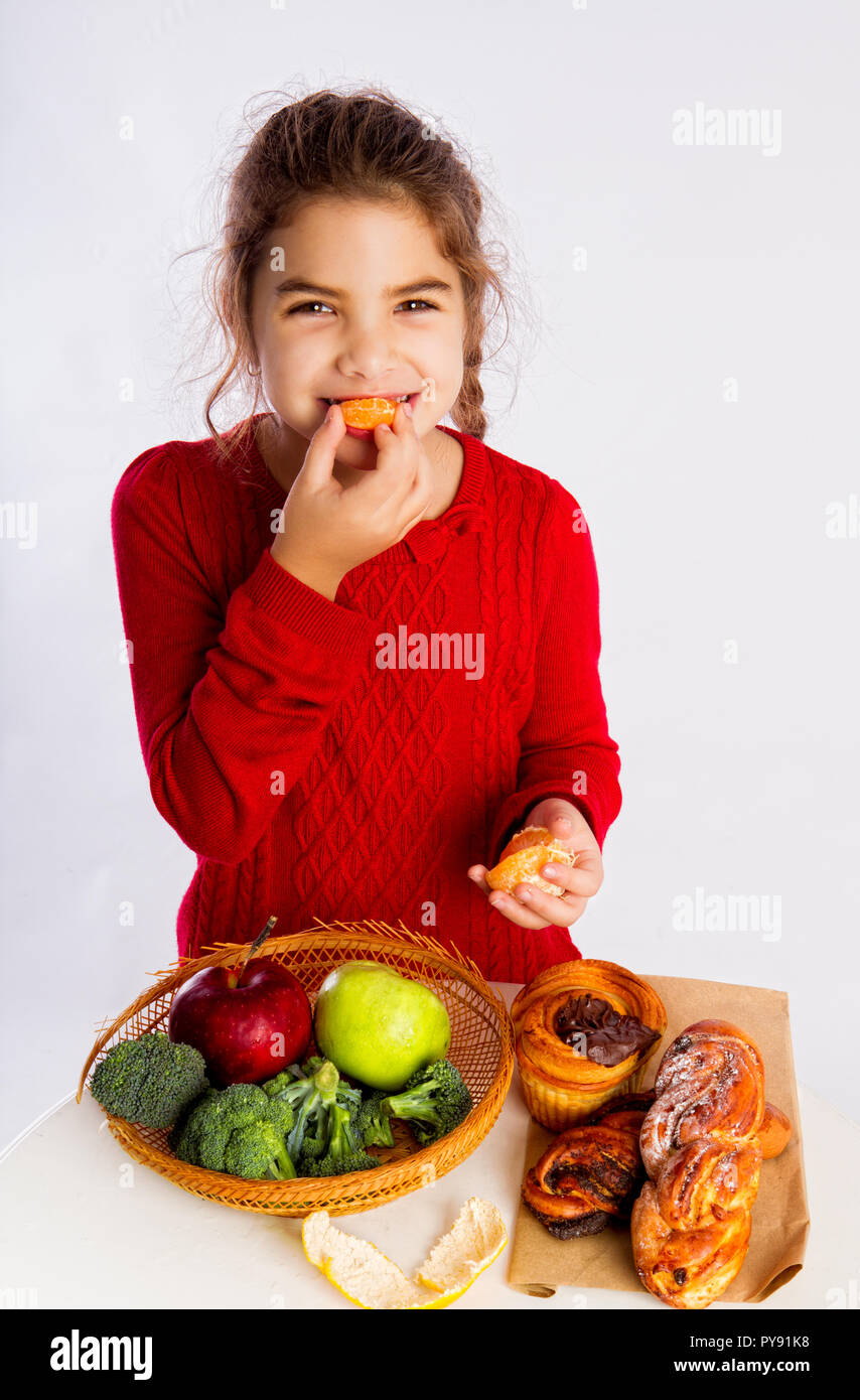 Little girl chooses what to eat, healthy food or buns Stock Photo - Alamy