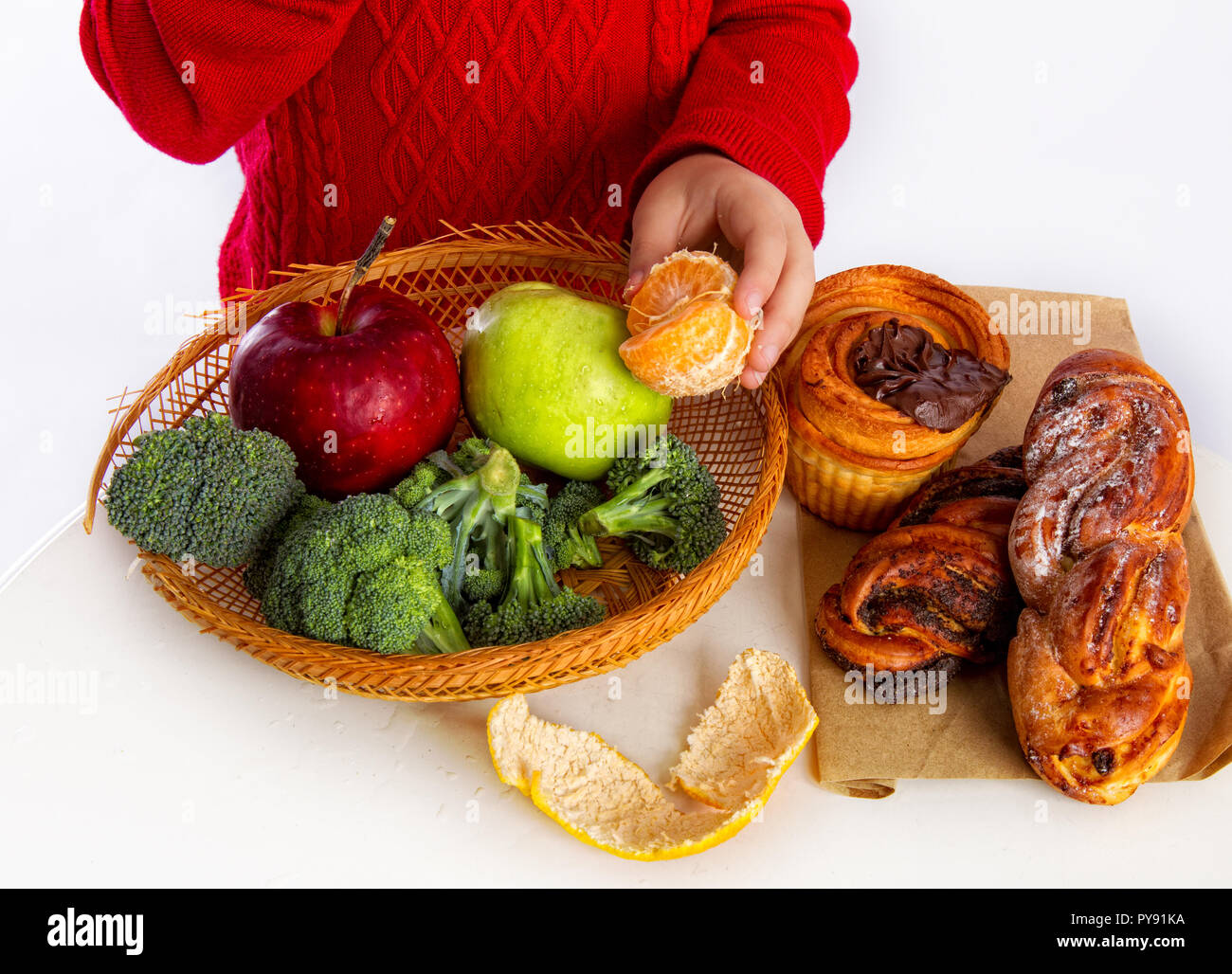 Little girl chooses what to eat, healthy food or buns Stock Photo - Alamy