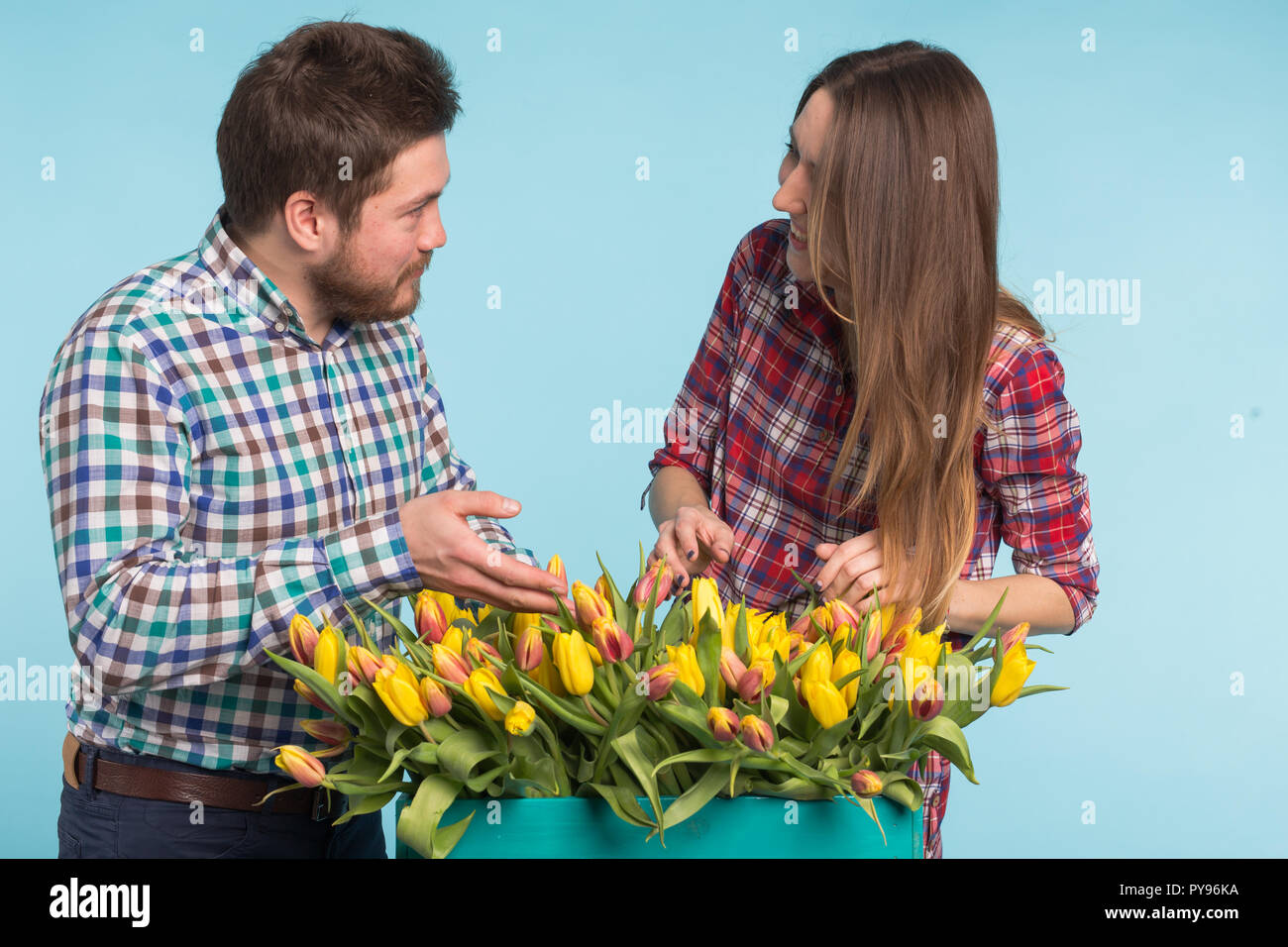 Happy man and woman florists holding box with tulips and laughing on ...
