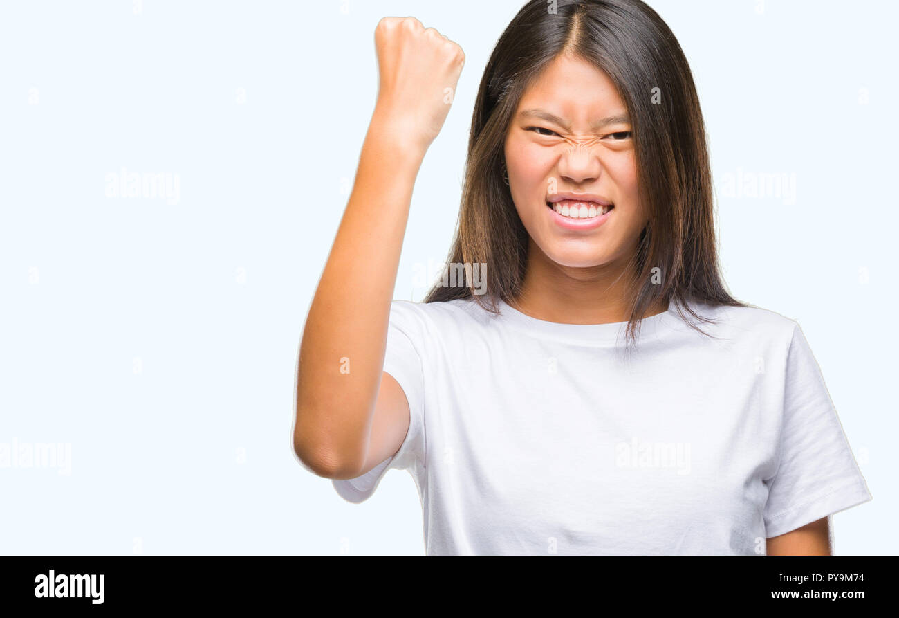 Young asian woman over isolated background angry and mad raising fist ...