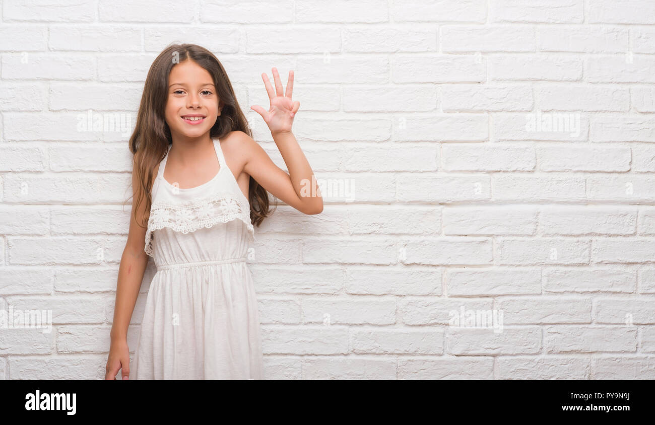 Young hispanic kid over white brick wall showing and pointing up with ...