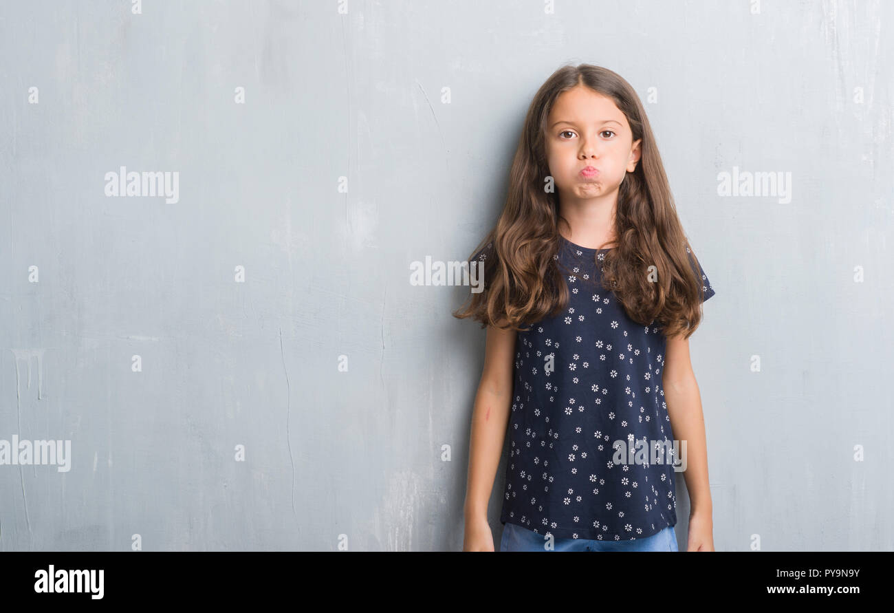 Young hispanic kid over grunge grey wall puffing cheeks with funny face ...