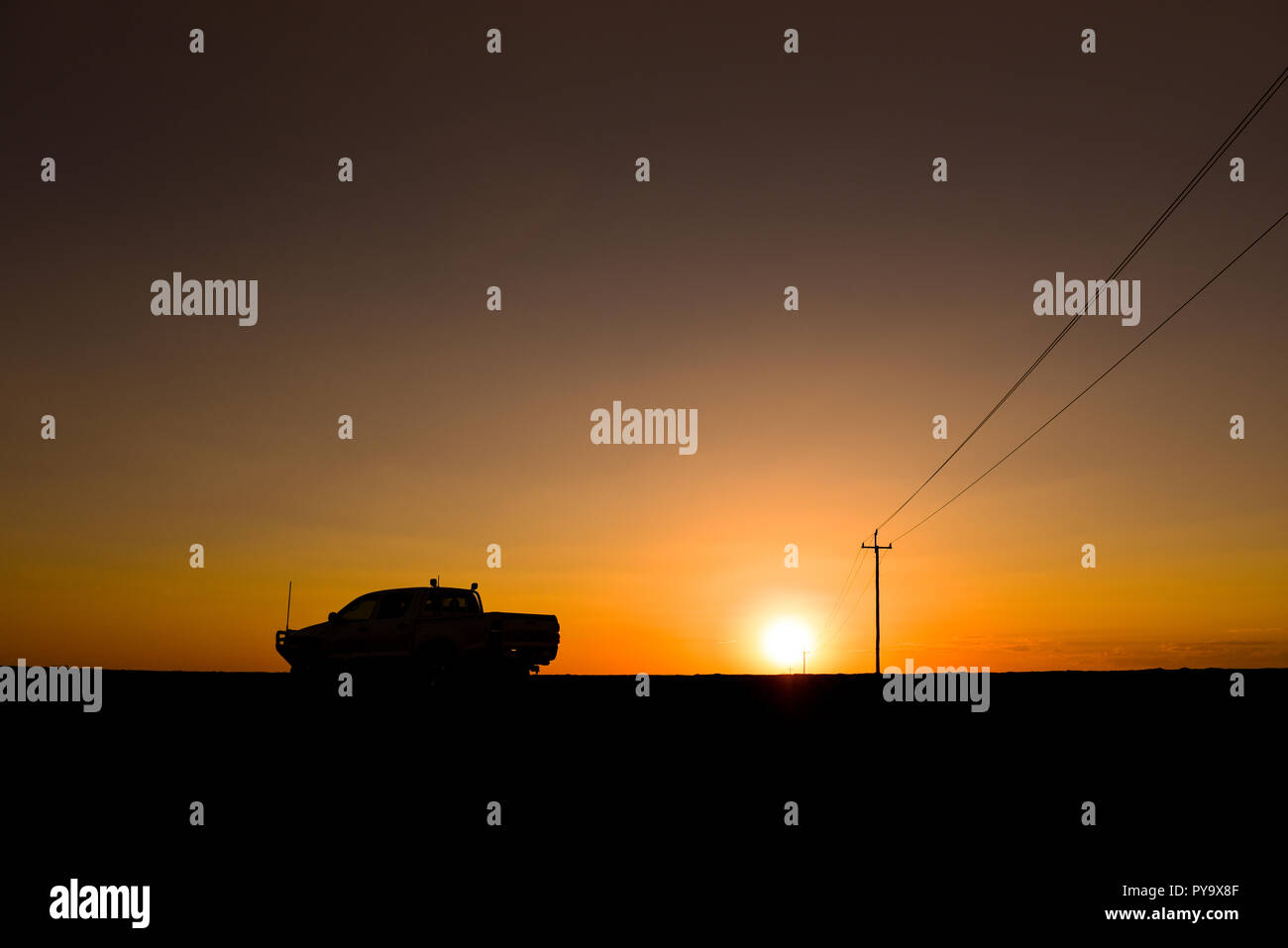 Side view of a ute car in the field next to the power line with ...