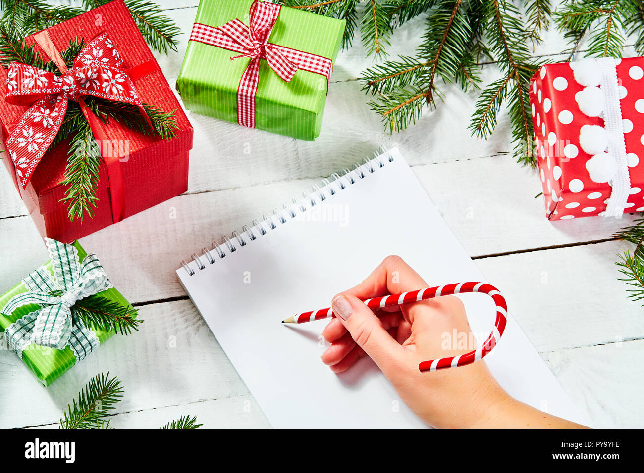 hand of a woman writing a letter to santa on an old white wooden table ...