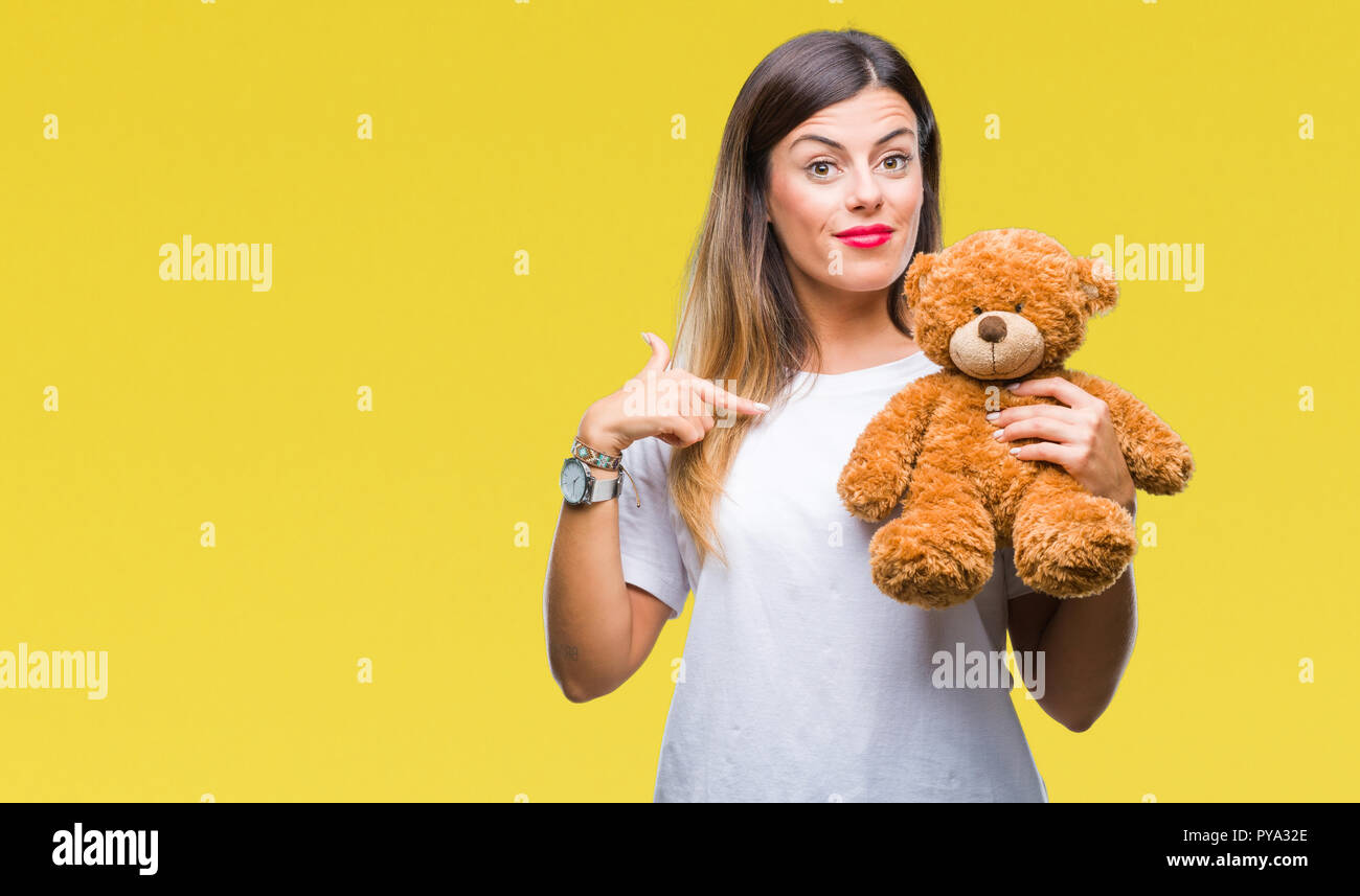 Young beautiful woman holding teddy bear plush over isolated background ...