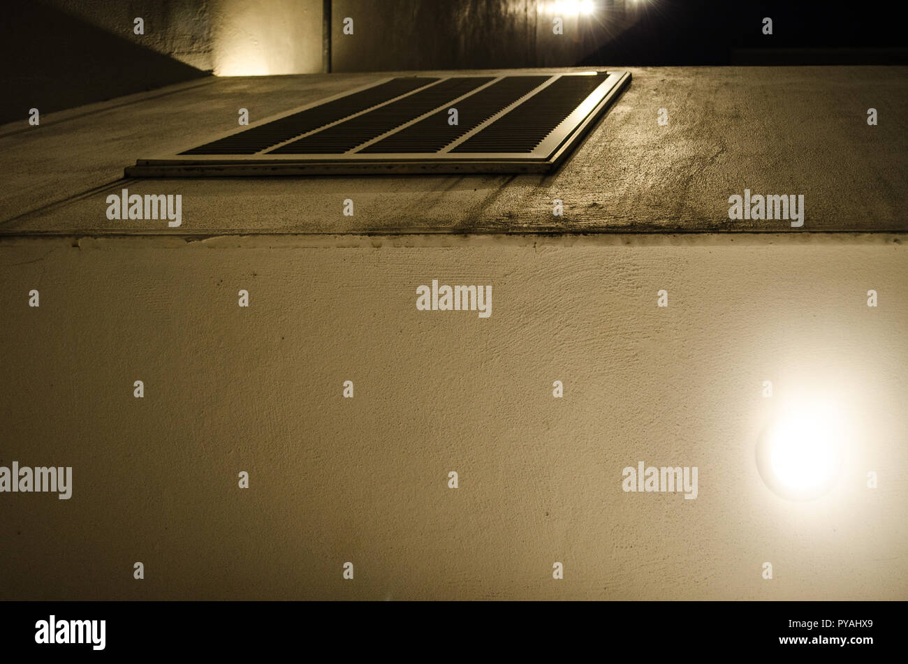 spots of yellow lights outside a gray building, on the urban street of ...