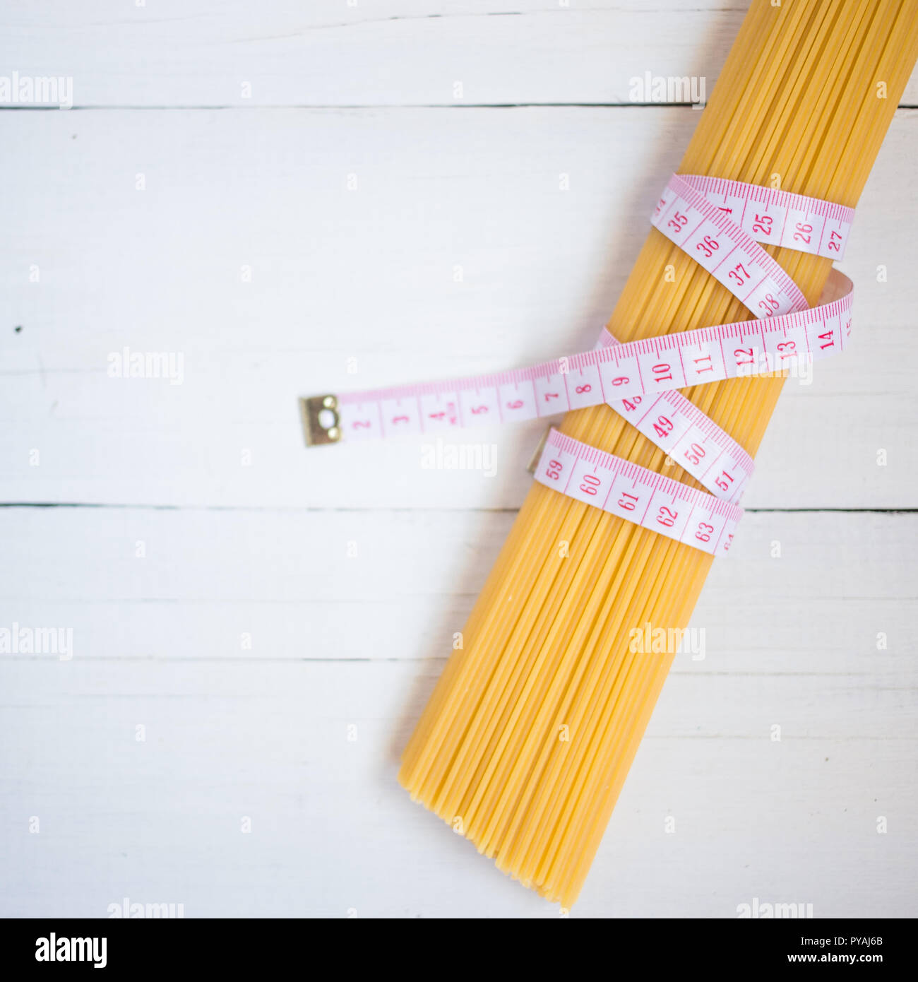 Measuring tape,diet theme. with bunch of uncooked Italian pasta ...