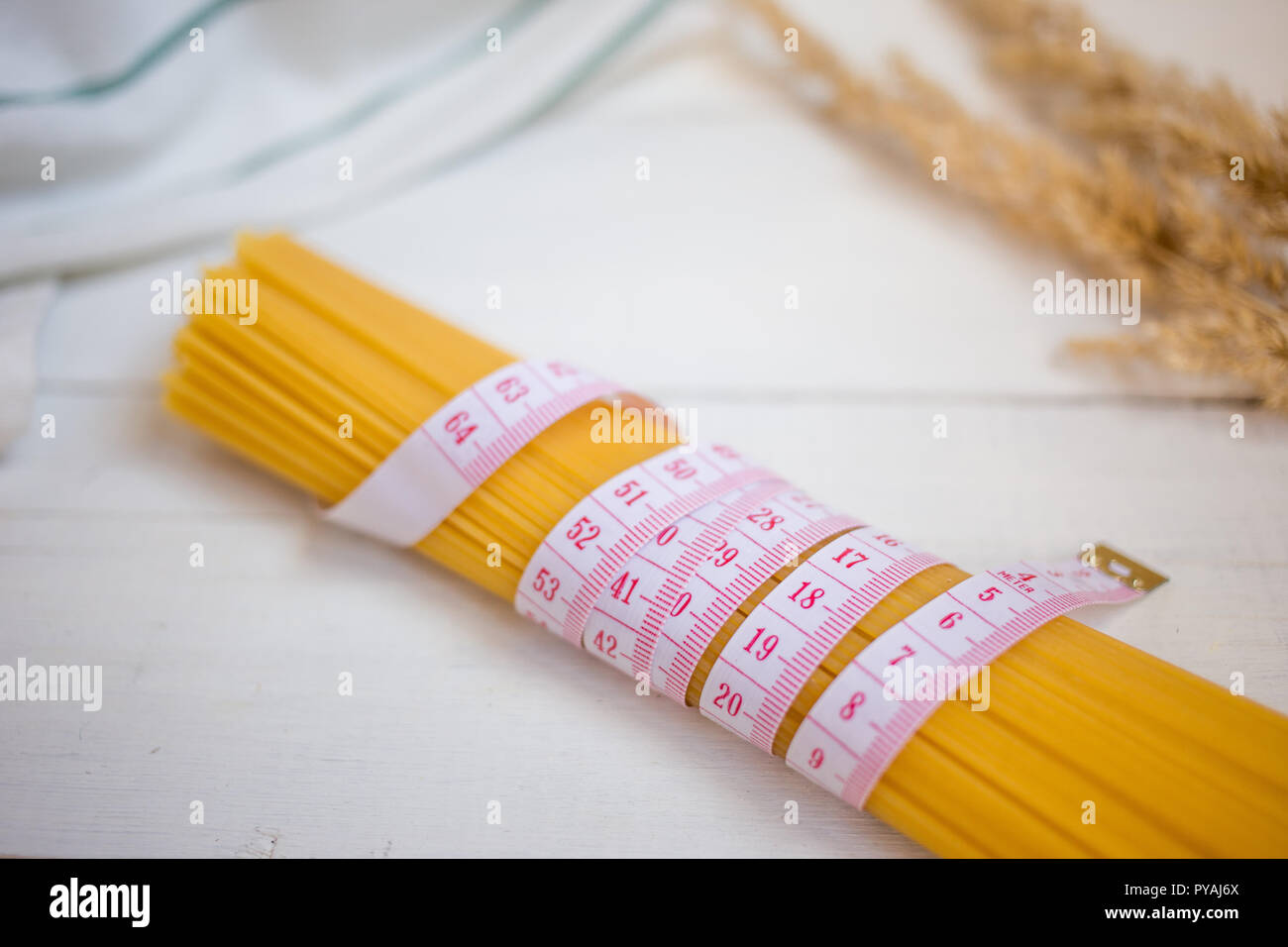 Measuring tape with bunch of uncooked Italian pasta spaghetti ...