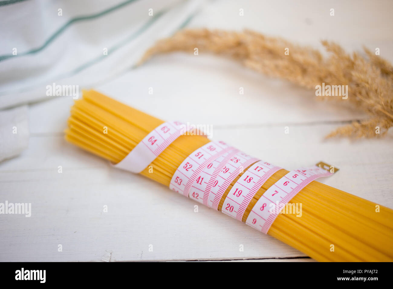 Measuring tape with bunch of uncooked Italian pasta spaghetti ...