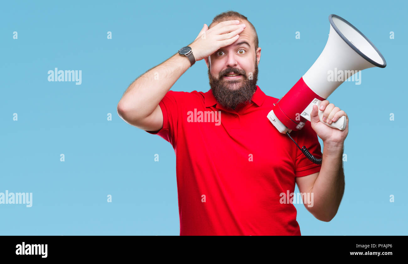 Young caucasian man shouting through megaphone over isolated background ...