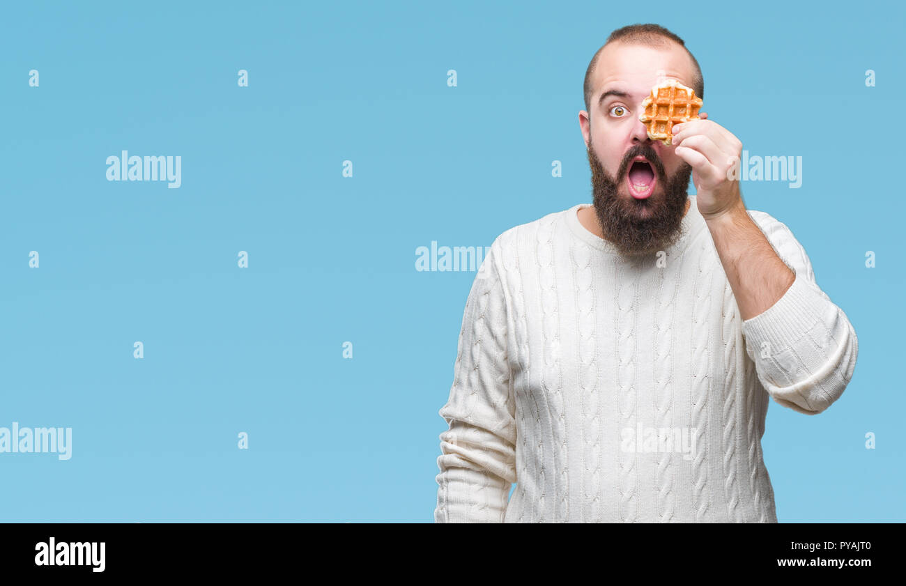 Young caucasian hipster man eating sweet waffle over isolated ...