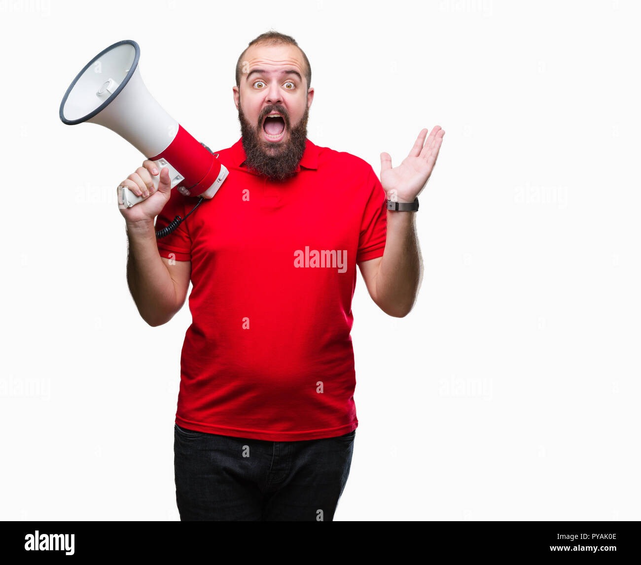 Young caucasian man shouting through megaphone over isolated background ...