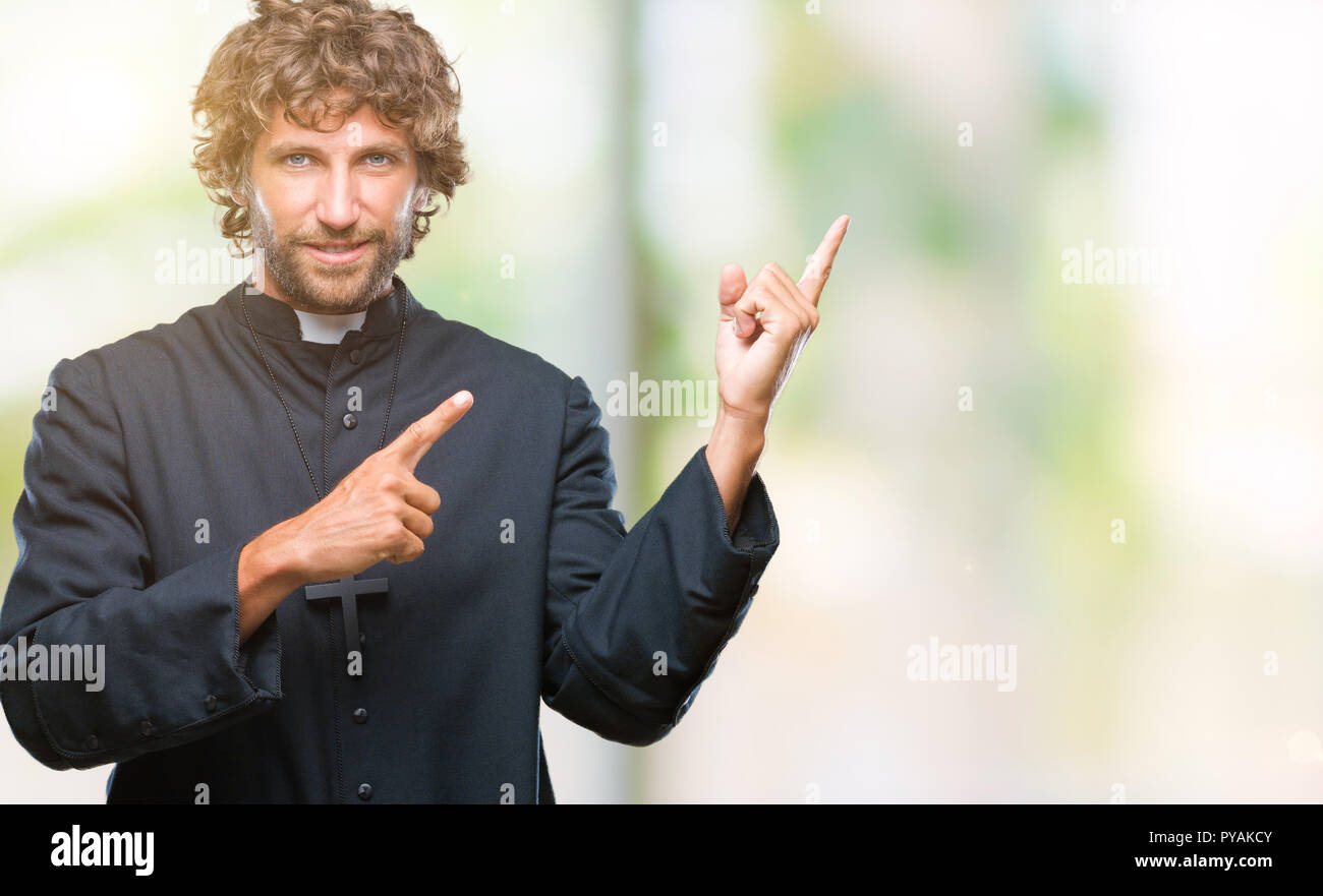 Handsome hispanic catholic priest man over isolated background smiling ...