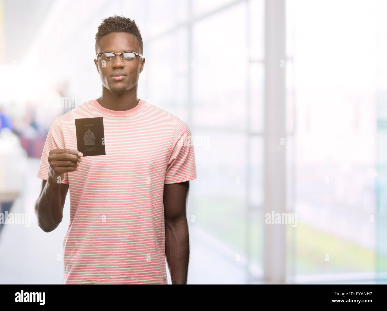 Young african american man holding canadian passport with a confident ...