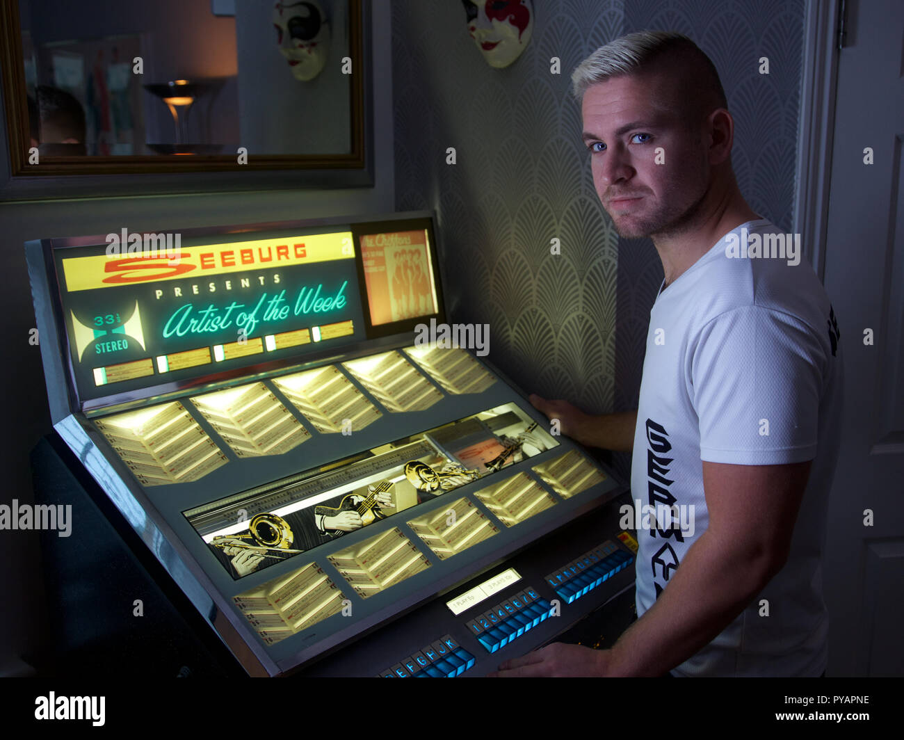 A young man standing by a Seeburg juke box, looking at camera , England ...
