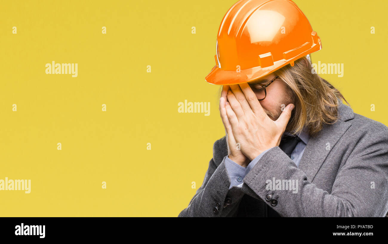 Young handsome architec man with long hair wearing safety helmet over ...