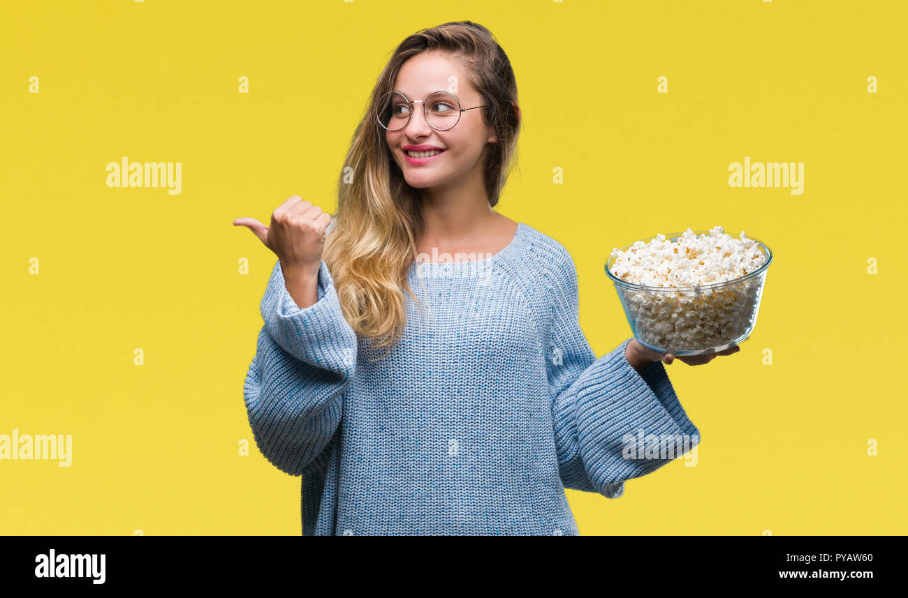 Young beautiful blonde woman eating popcorn over isolated background ...