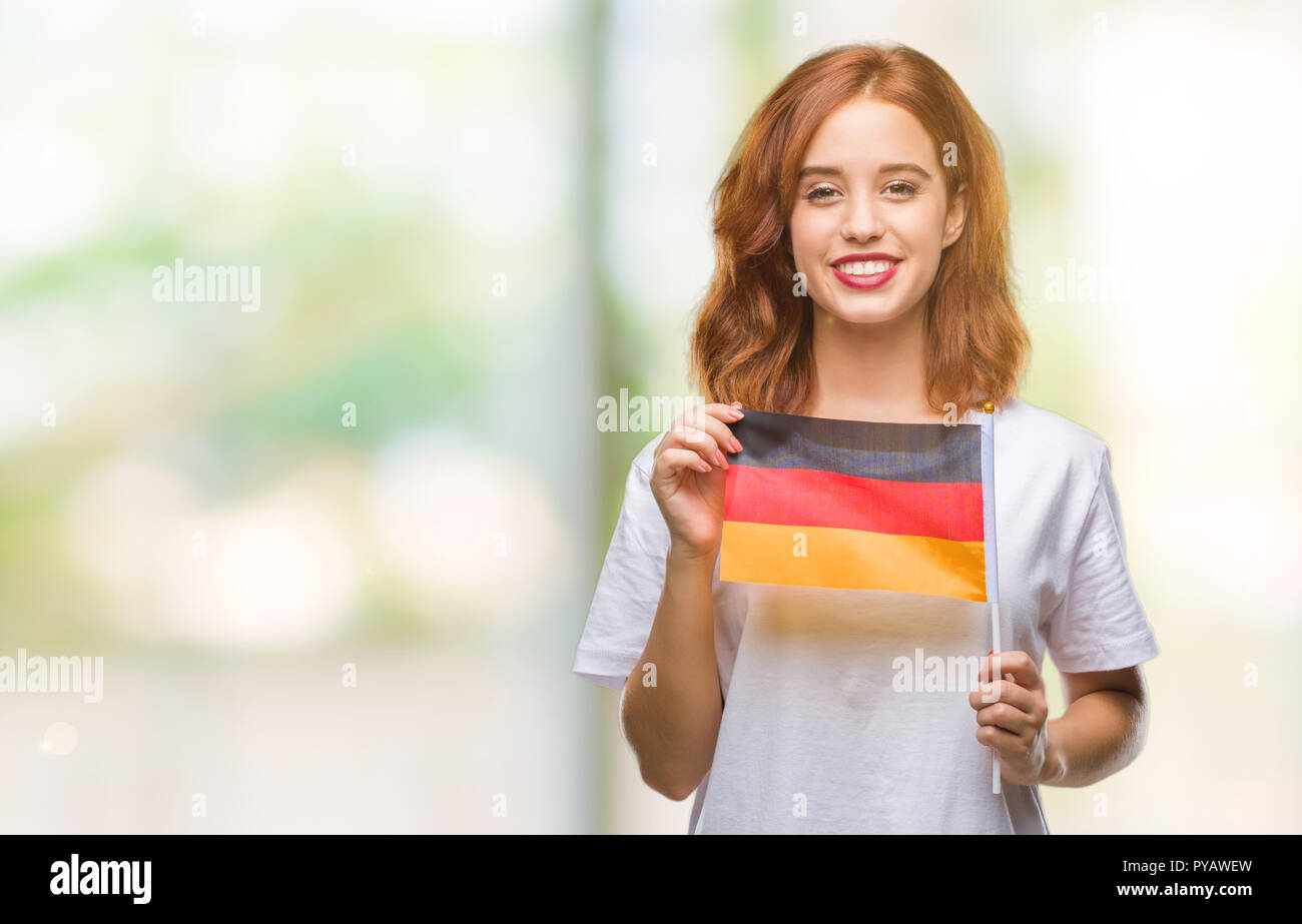 Young beautiful woman holding flag of germany over isolated background ...