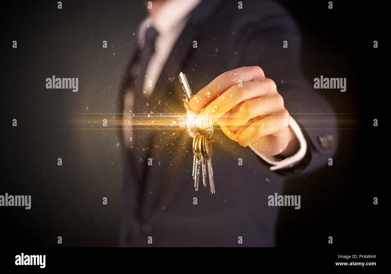 Businessman hand over shiny keys in dark suit with dark background ...