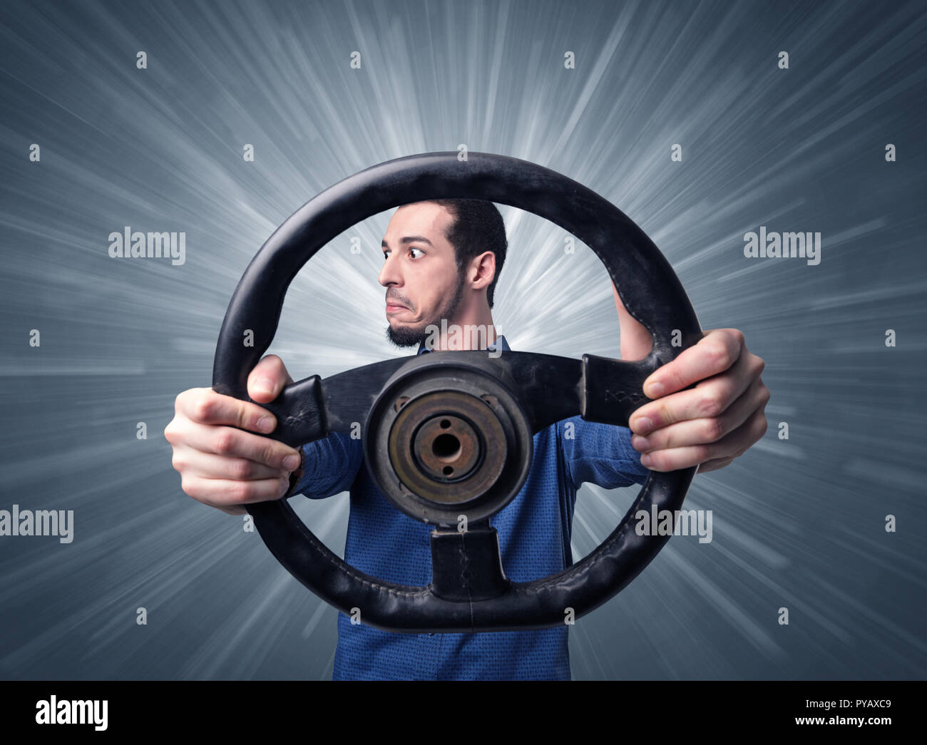 Young man holding black steering wheel with white lines behind him ...