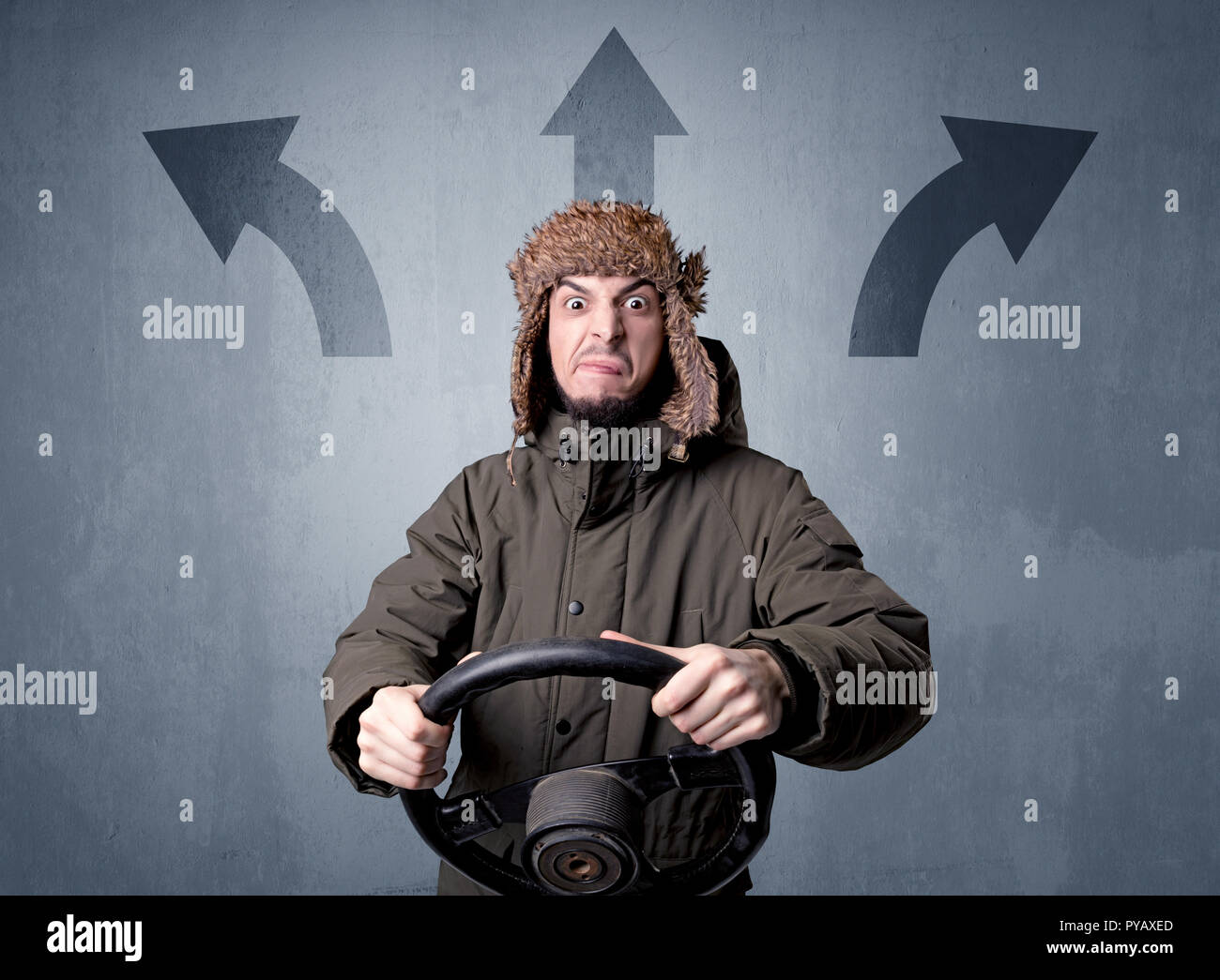 Young man holding black steering wheel with three arrows above his head ...