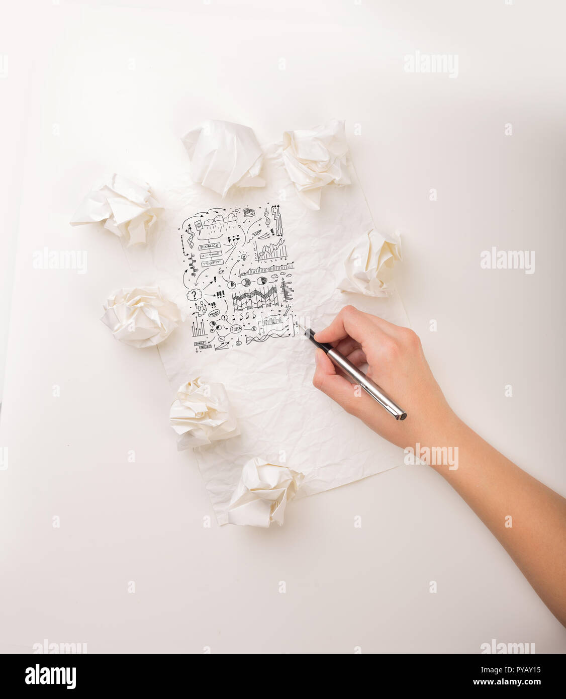 Female hand next to a few crumpled paper balls drawing charts and ...
